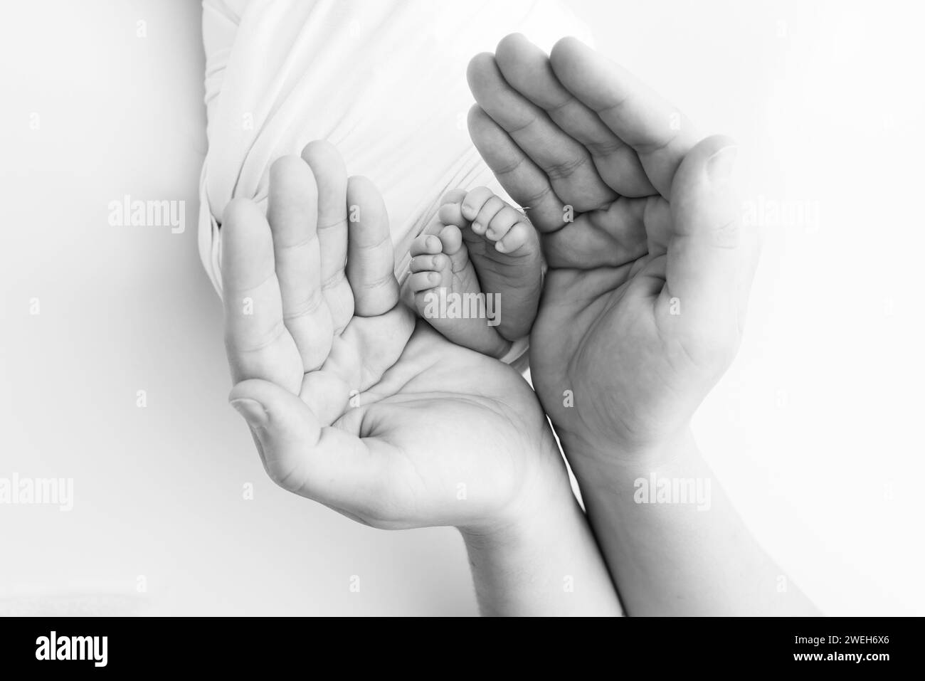The palms of the father, the mother are holding the foot of the newborn ...