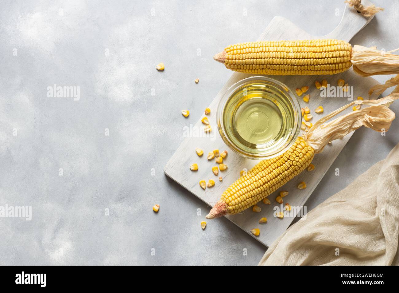 Corn oil in glass bowl with dried corn groats and kernels on rustic ...
