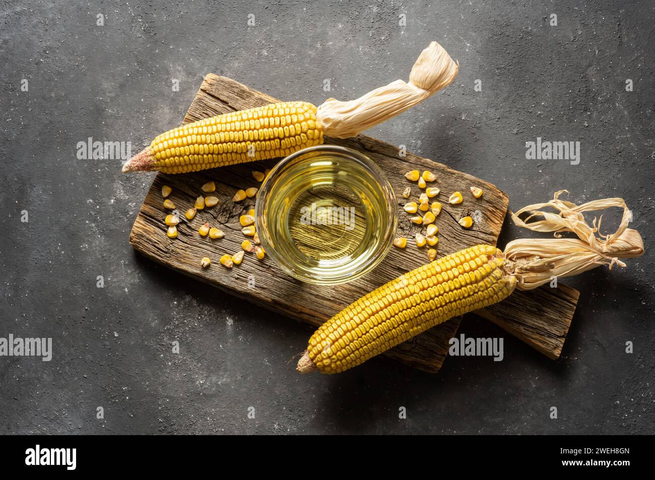 Corn oil in glass bowl with dried corn groats and kernels on rustic ...