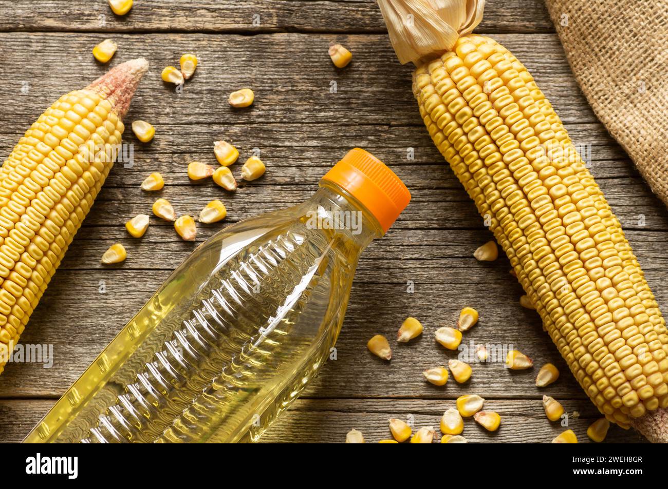 Corn oil in plastic bowl with dried corn groats and kernels on rustic ...
