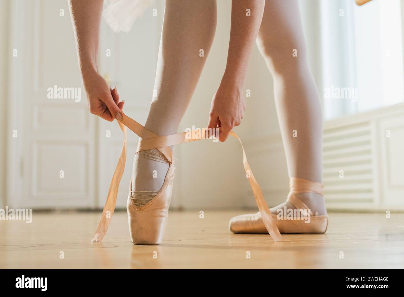 Ballerina puts on pointe shoes on leg in dance class. Classical ballet ...