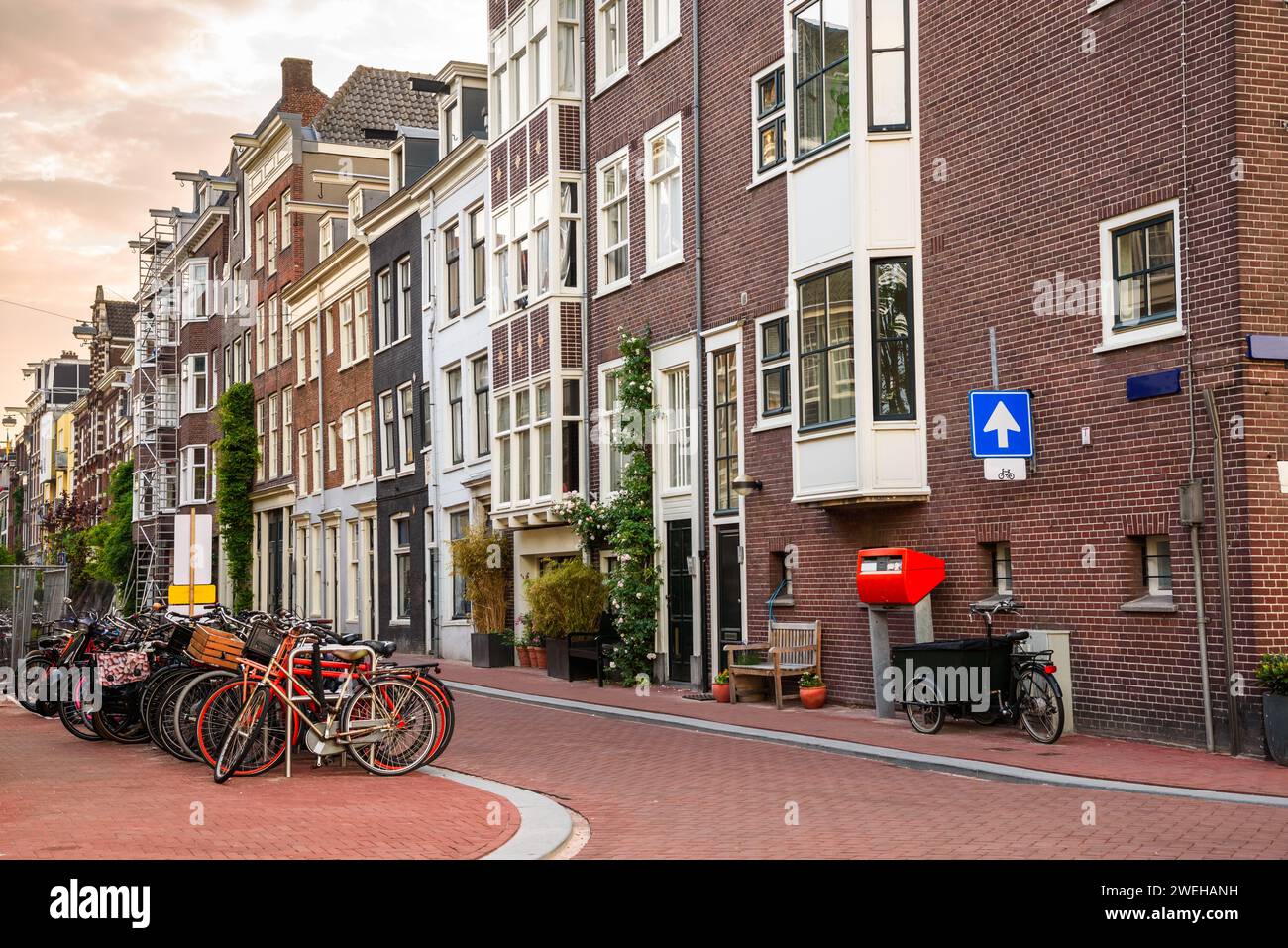 Traditional Duch townhouses along a narrow brick street in Amsterdam at ...