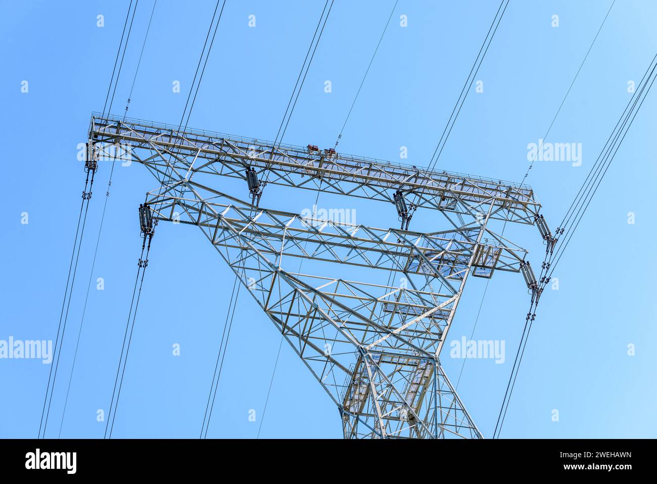 Detail of the top of a tall high voltage electricity pylon against ...