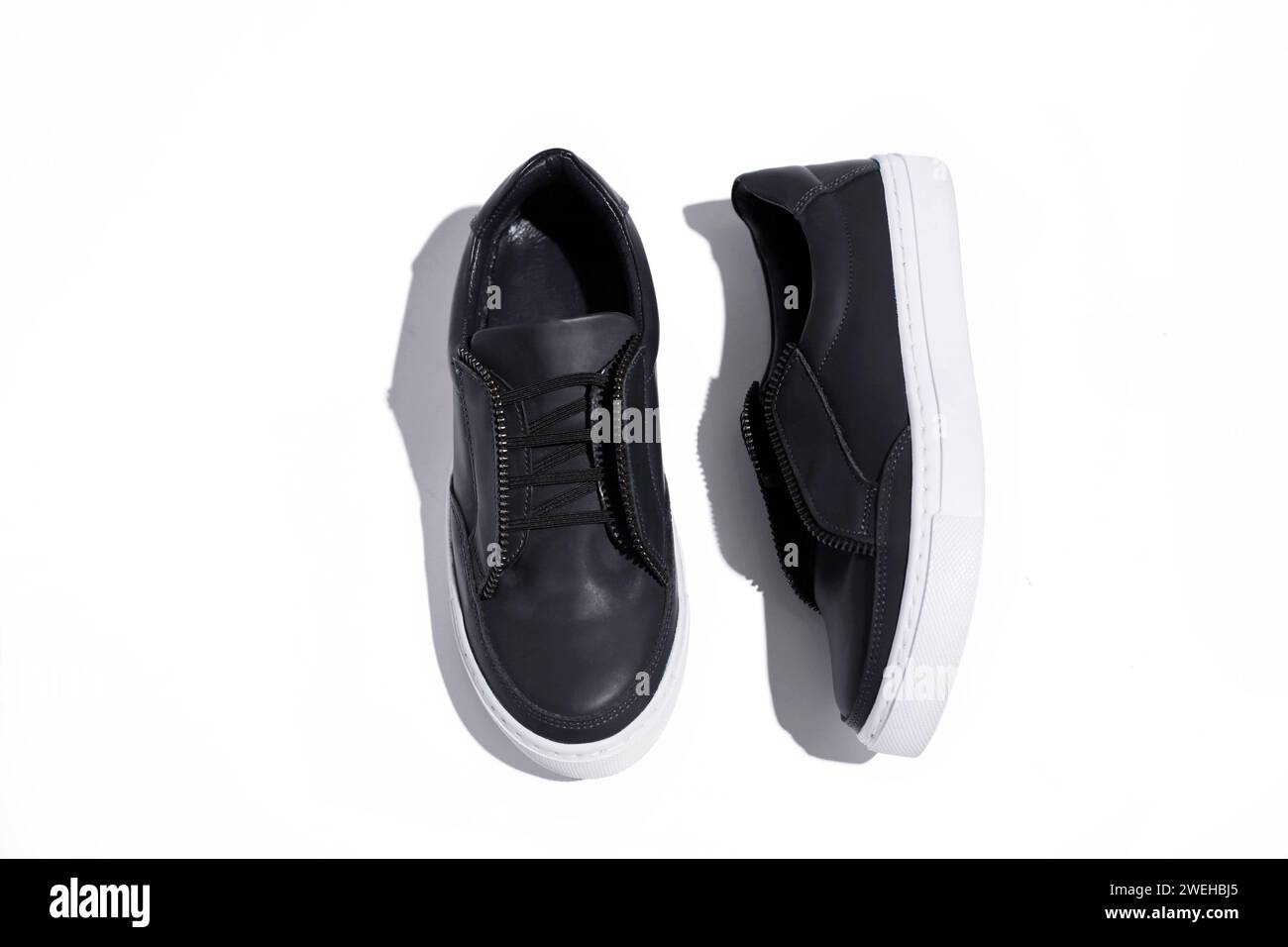 black sneakers on a white background top view with hard shadows. Women ...