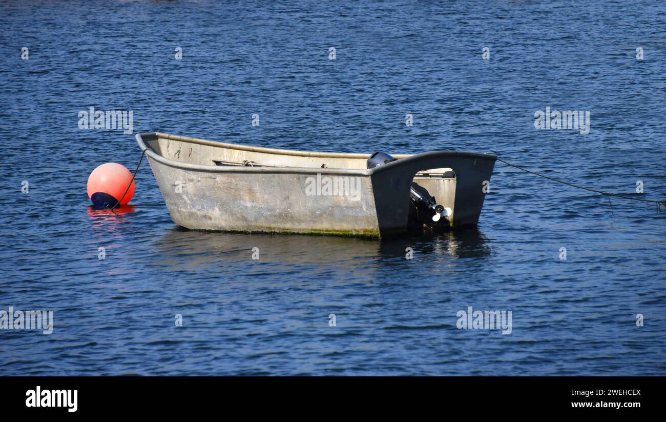 Aluminum motor boat floats in Yaquina Bay, Newport, Oregon. It is tied ...