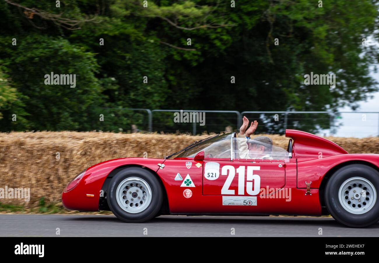 Waving to the crowd in a Alfa Romeo Tipo 33 racing car at the Goodwood ...