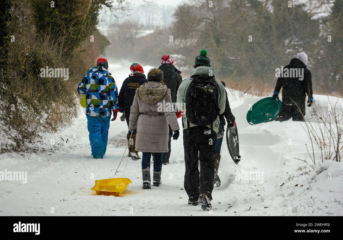 A group of people walking in the snow dragging a yellow sledge Stock ...