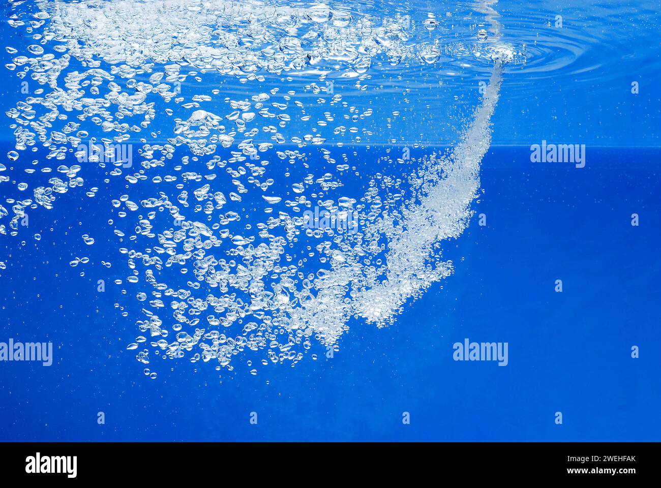 a thin jet of water penetrates the water surface and produces many air ...