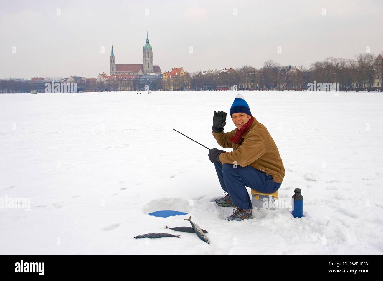 a man sits ice fishing on the Theresienwiese, with three freshly caught ...