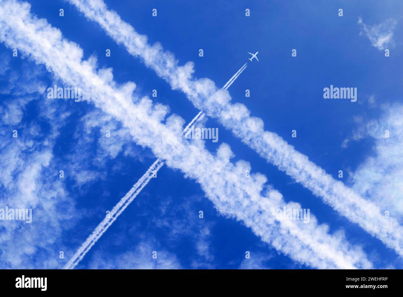 a passenger aircraft with contrails in the blue sky crosses other ...