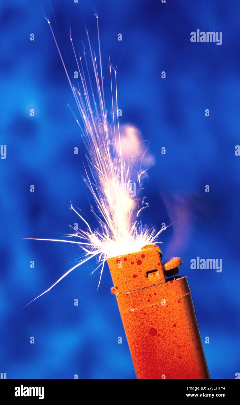 an orange-red lighter sprays sparks against a blue background Stock ...