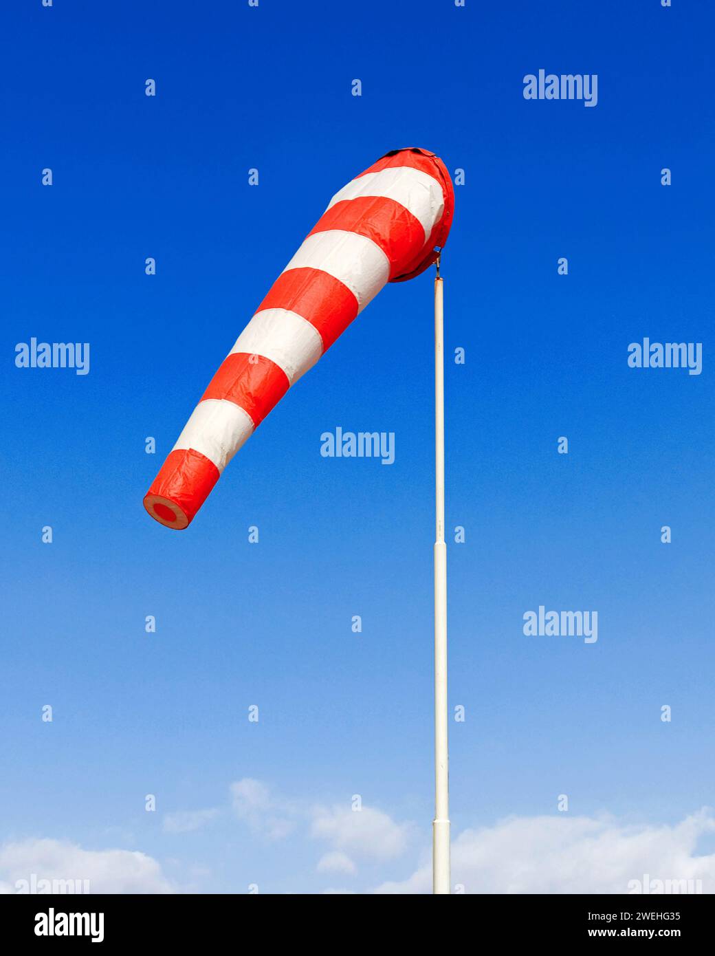 a red and white windsock blows in a light breeze against a blue sky ...