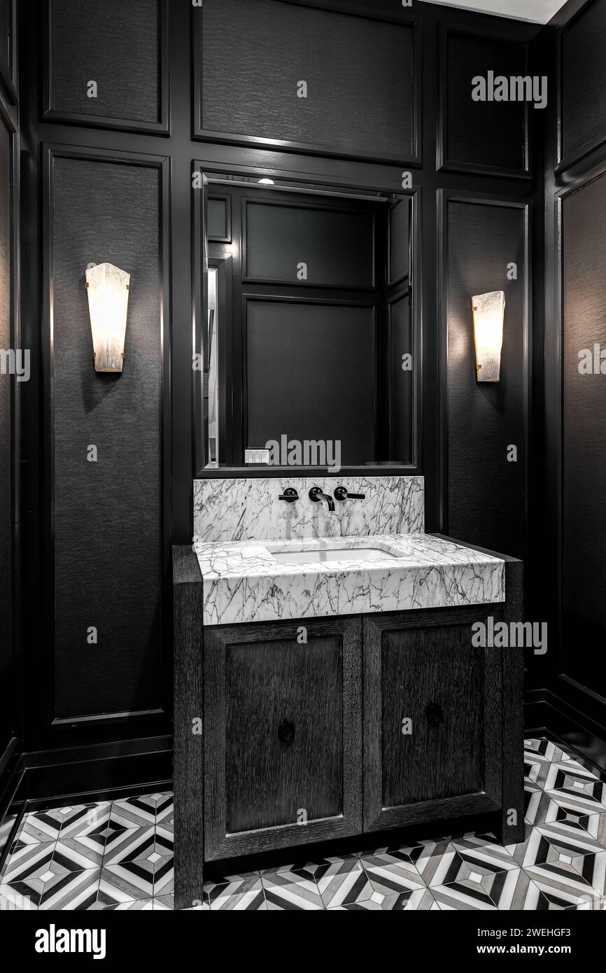 A bathroom with black wainscoting and wallpaper, a dark grey wood ...