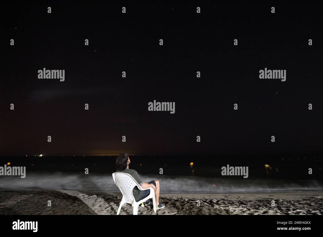 Young man sitting on a caribbean beach watching starry night Stock ...