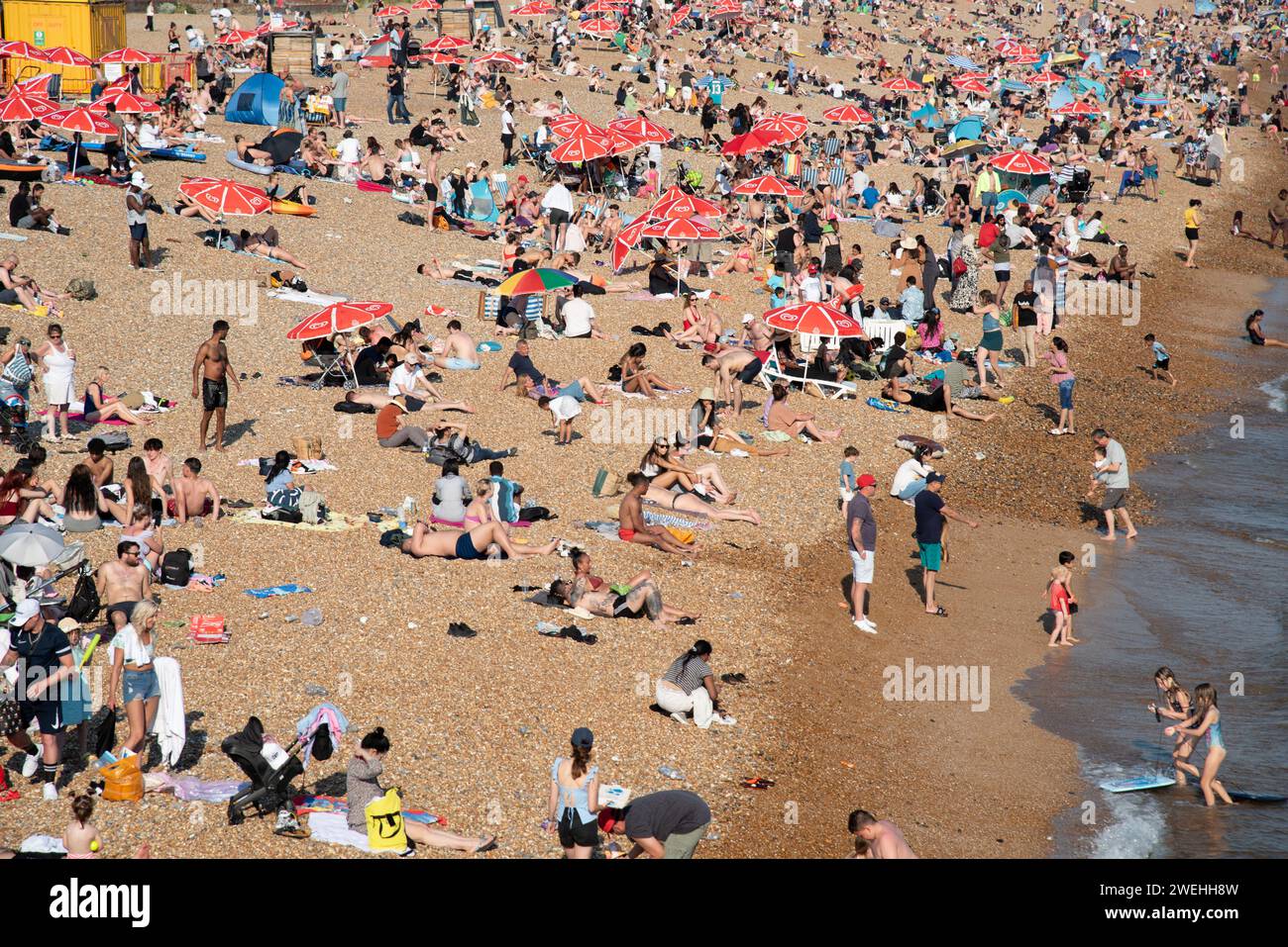 Crowd of British people sunbathing swimming and relaxing in the beach ...