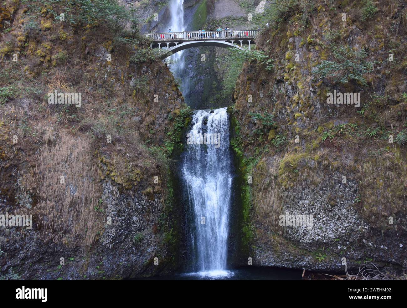 Double tiered Multnomah Falls cascades down rock wall and spills under ...