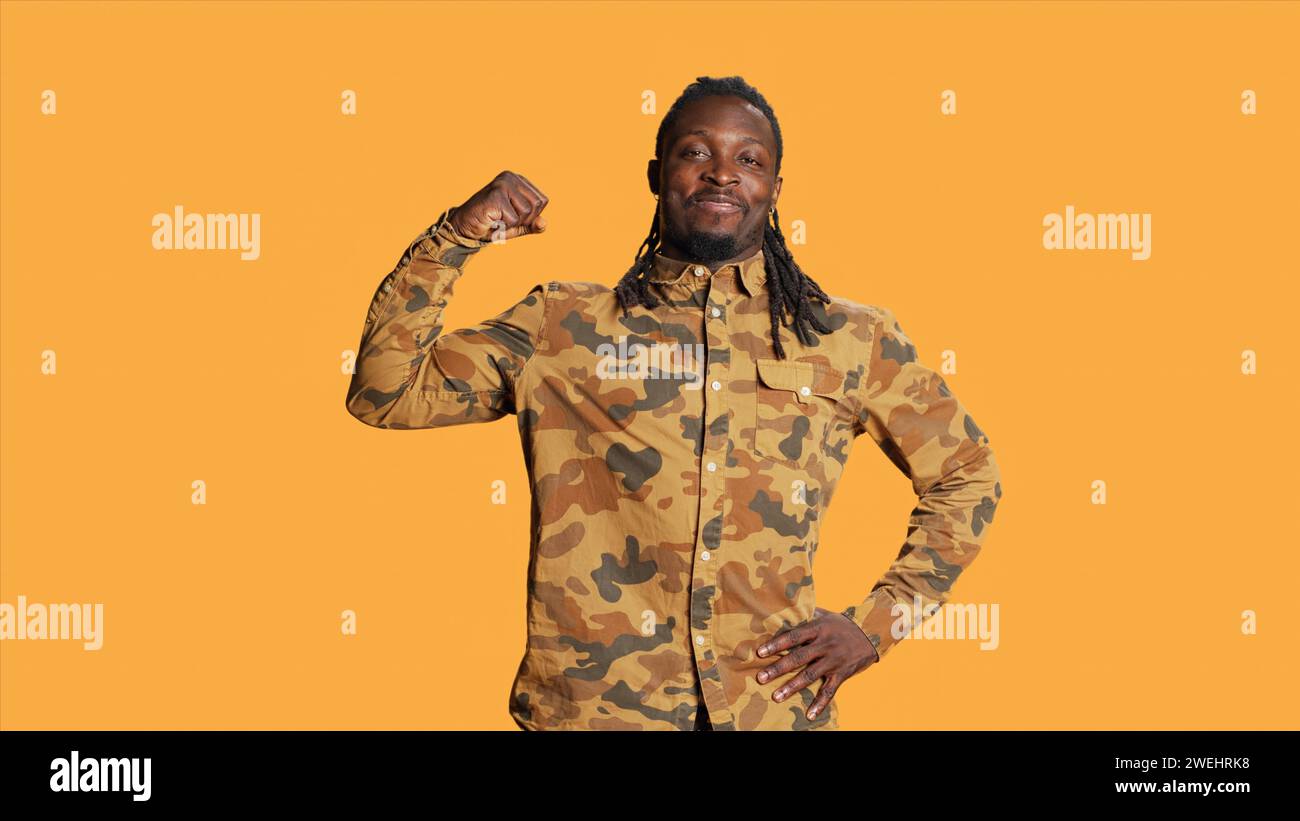 Athletic person flexing his arms muscles in studio and pointing up ...