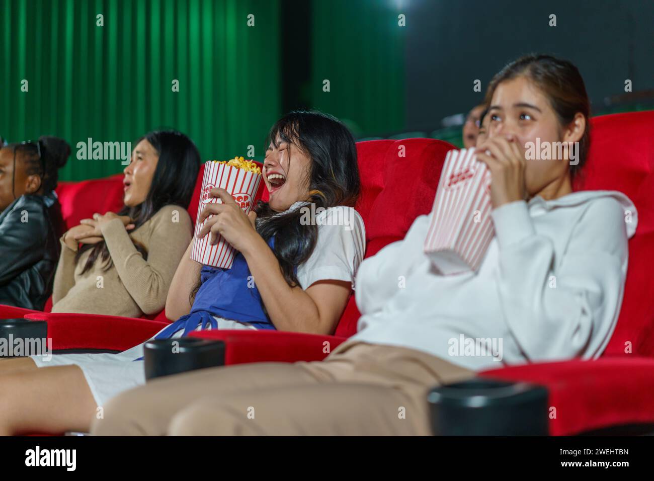 Individuals react to a horror movie on the big screen. This candid ...