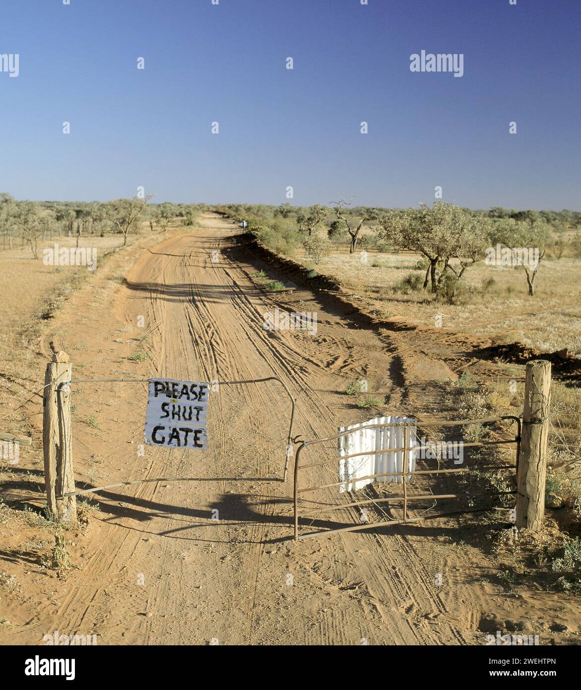 Dirt track in outback Queensland with please shut gate sign for passing ...