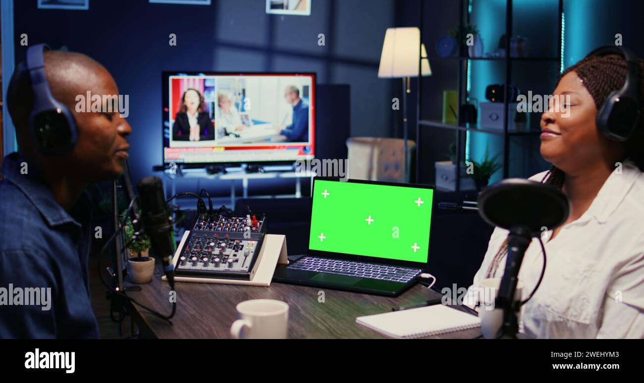 Green screen laptop next to vlogger show host and guest talking in neon ...