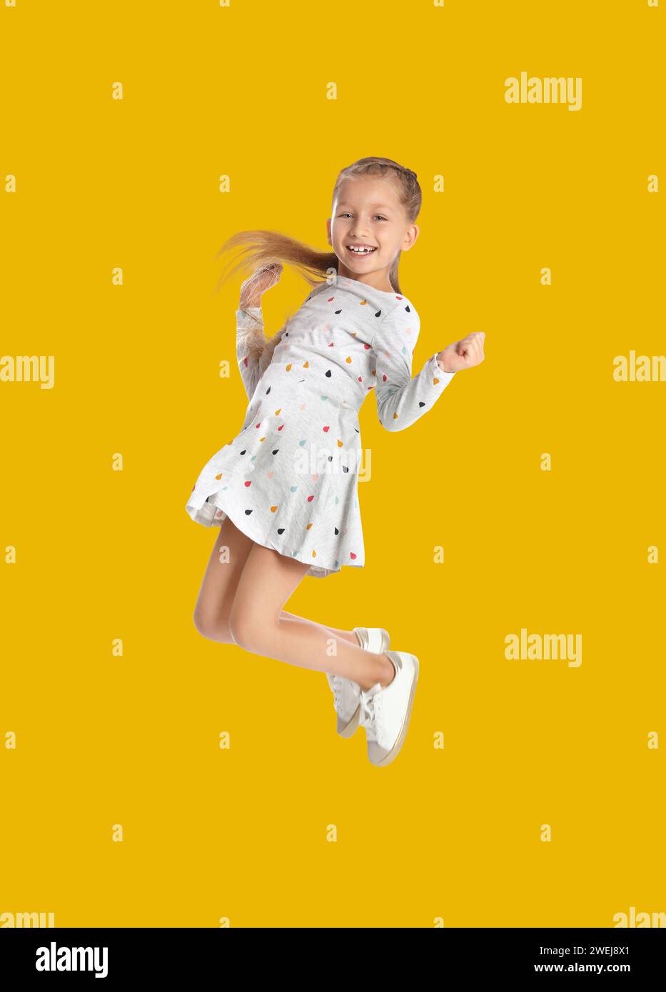 Happy cute girl jumping on golden background Stock Photo - Alamy