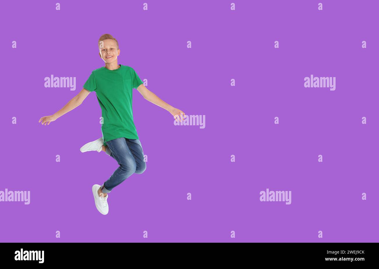Happy boy jumping on violet background, space for text Stock Photo - Alamy