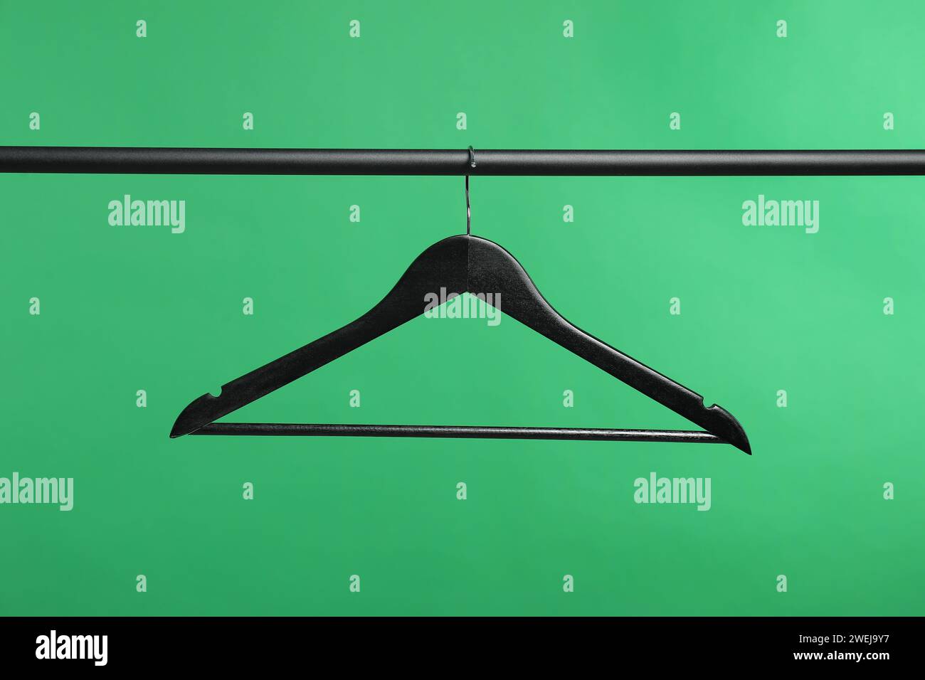 Empty clothes hanger on rack against green background Stock Photo - Alamy