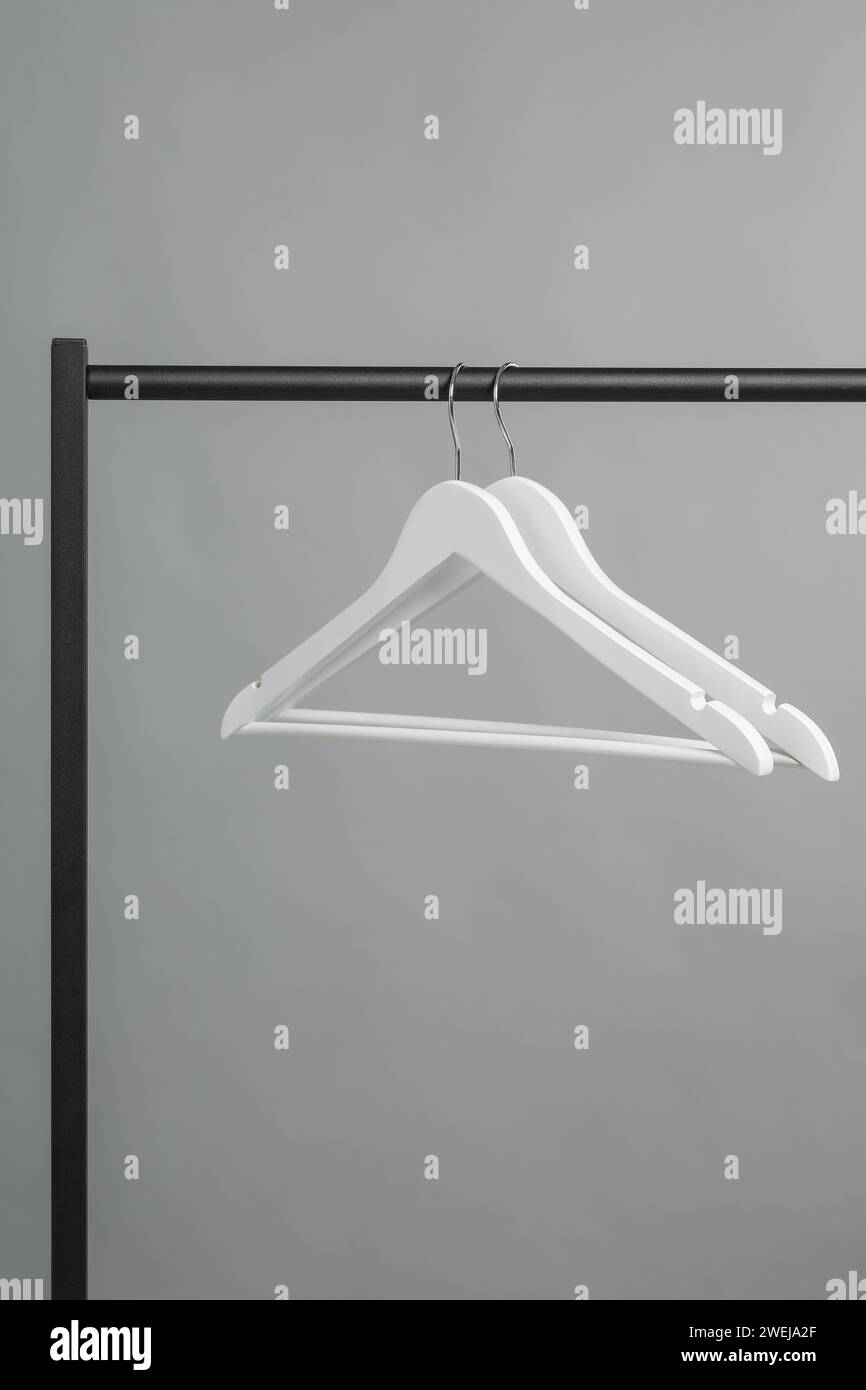 Empty clothes hangers on rack against grey background Stock Photo - Alamy
