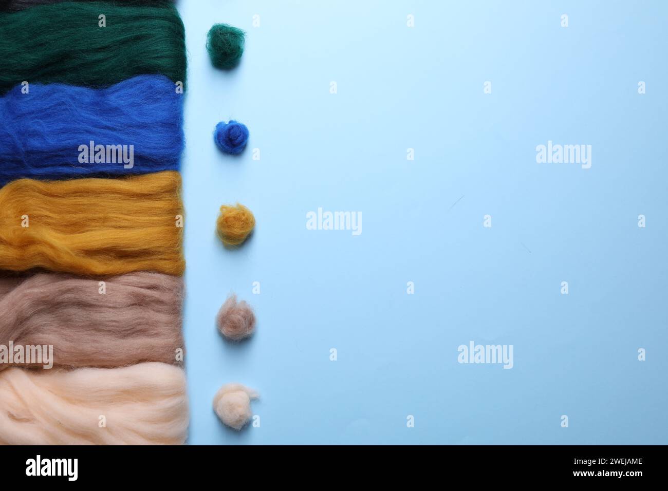 Colorful felting wool and balls on light blue background, flat lay ...