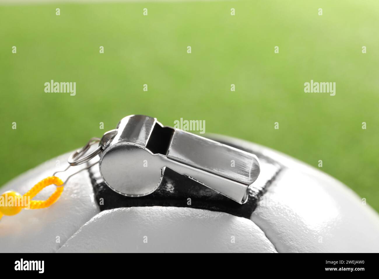 Football referee equipment. Soccer ball and metal whistle on green ...
