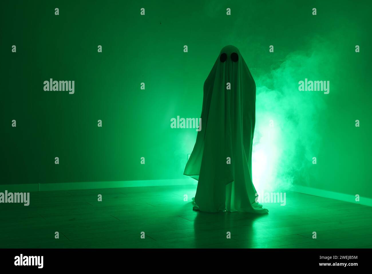 Creepy ghost. Woman covered with sheet in green light, space for text ...