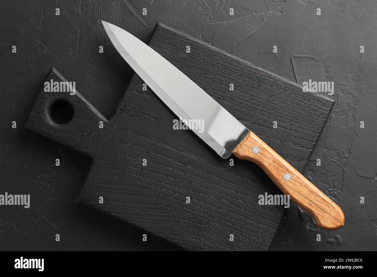 One sharp knife and board on dark textured table, top view Stock Photo ...