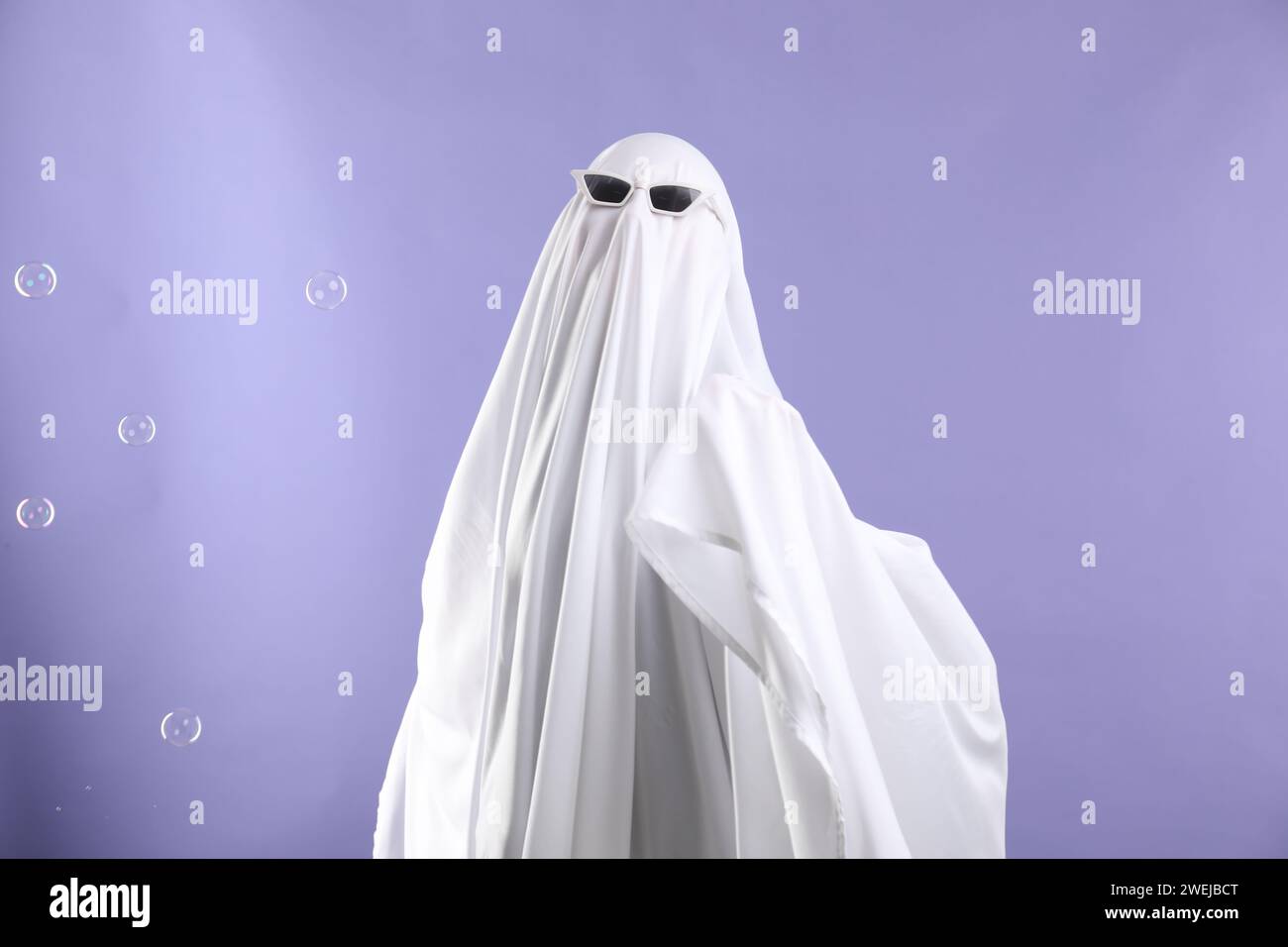 Funny ghost. Person in white sheet, sunglasses and soap bubbles on ...