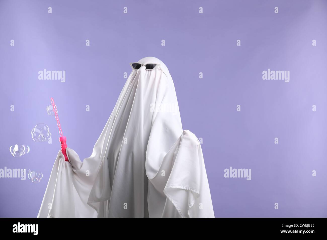 Funny ghost. Person in white sheet, sunglasses and soap bubbles on ...
