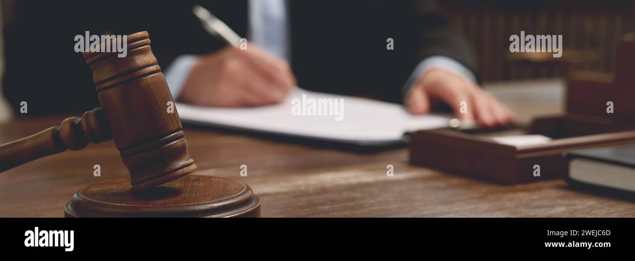Lawyer working with document at wooden table in office, focus on gavel ...