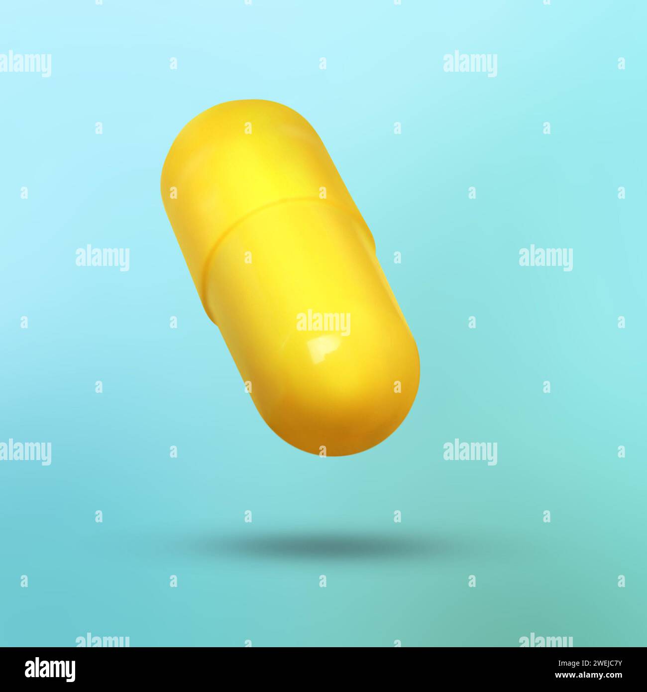 Yellow vitamin capsule in air on light blue background Stock Photo - Alamy