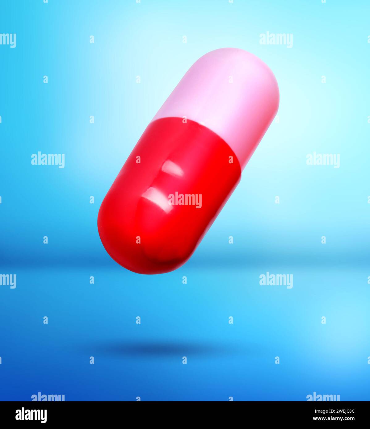 Colorful vitamin capsule in air on light blue gradient background Stock ...