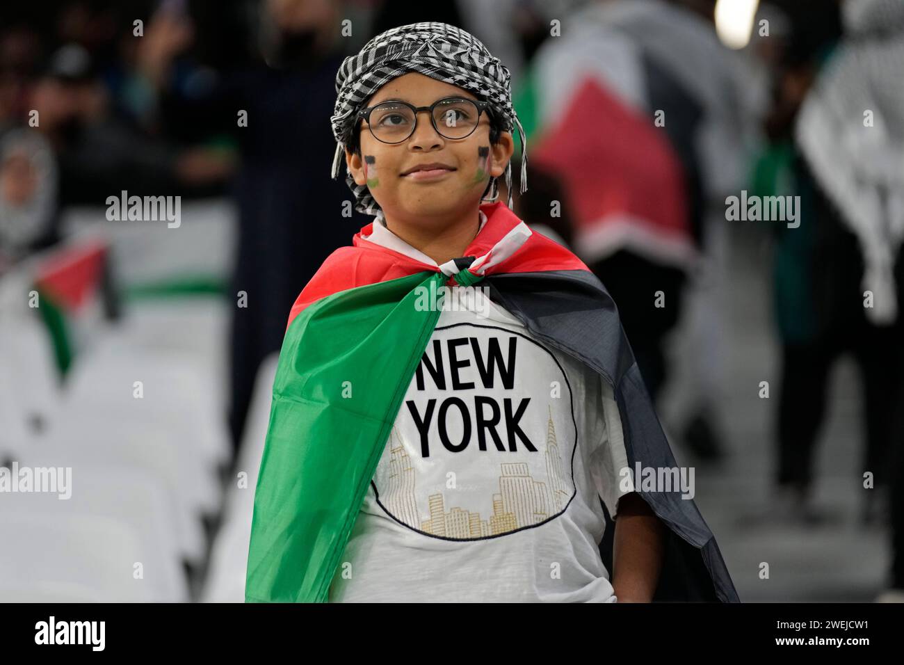 A young fan wears a Palestinian keffiyeh, a traditional Arab headdress ...