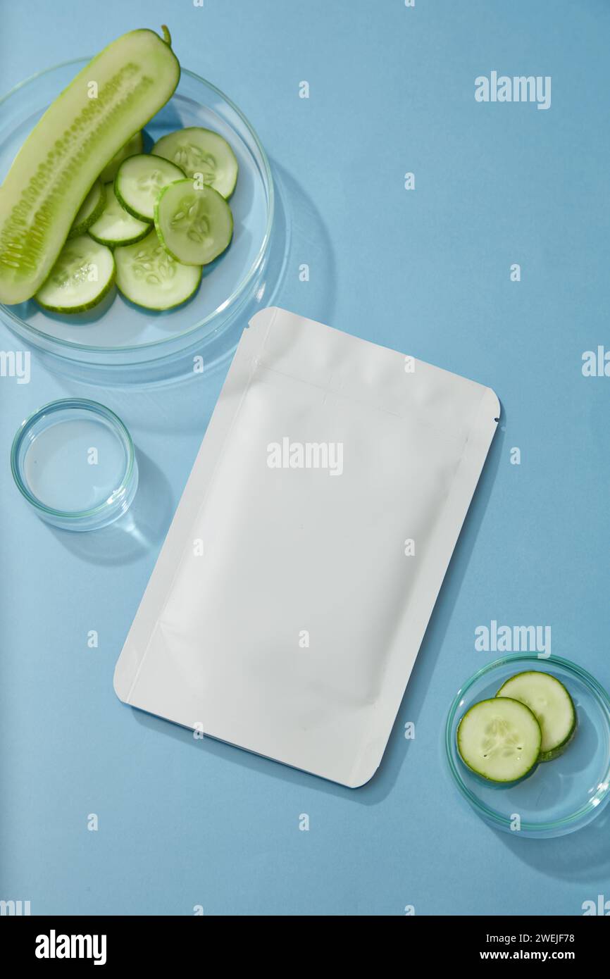 Mockup of a cucumber sheet mask on blue background with cucumber slices ...