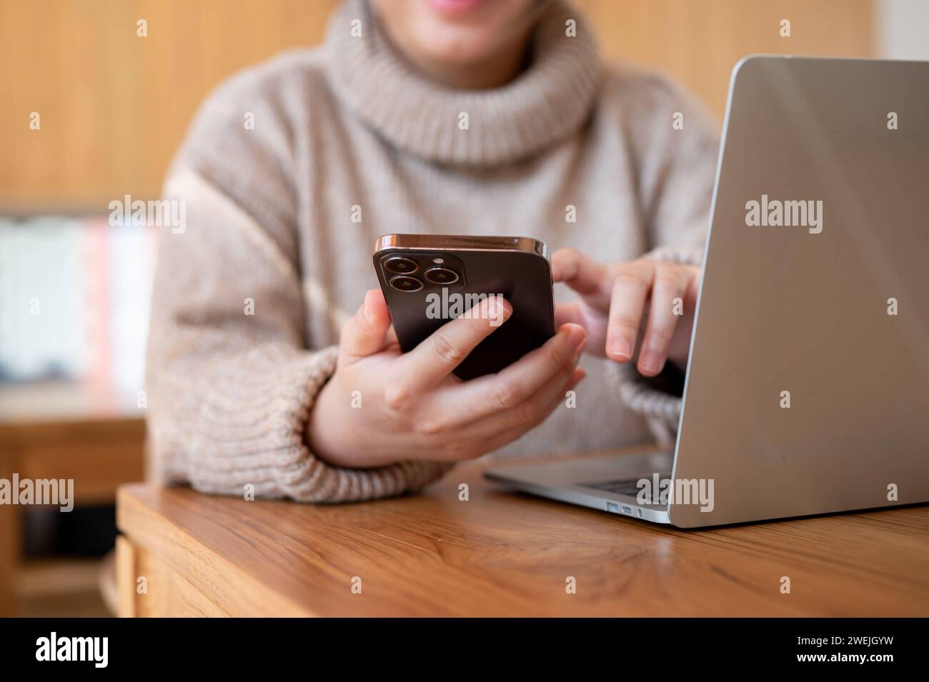Close-up image of a positive Asian woman in a cosy knitted sweater is ...