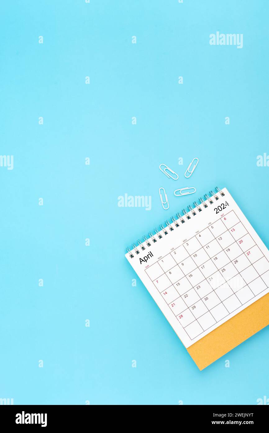 Desk calendar for April 2024 and white paper clip on a light blue color ...