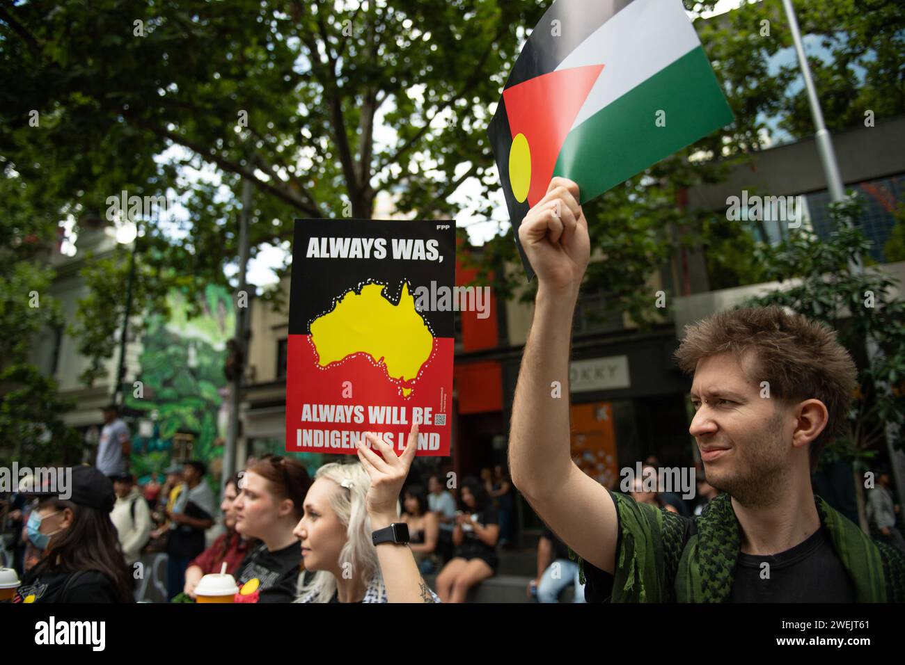 26th January 2024, Melbourne, Australia. A protesters hold signs, one ...