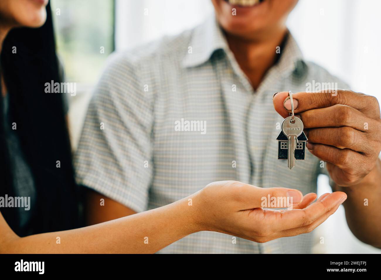 A delighted couple celebrates new homeownership displaying keys to ...