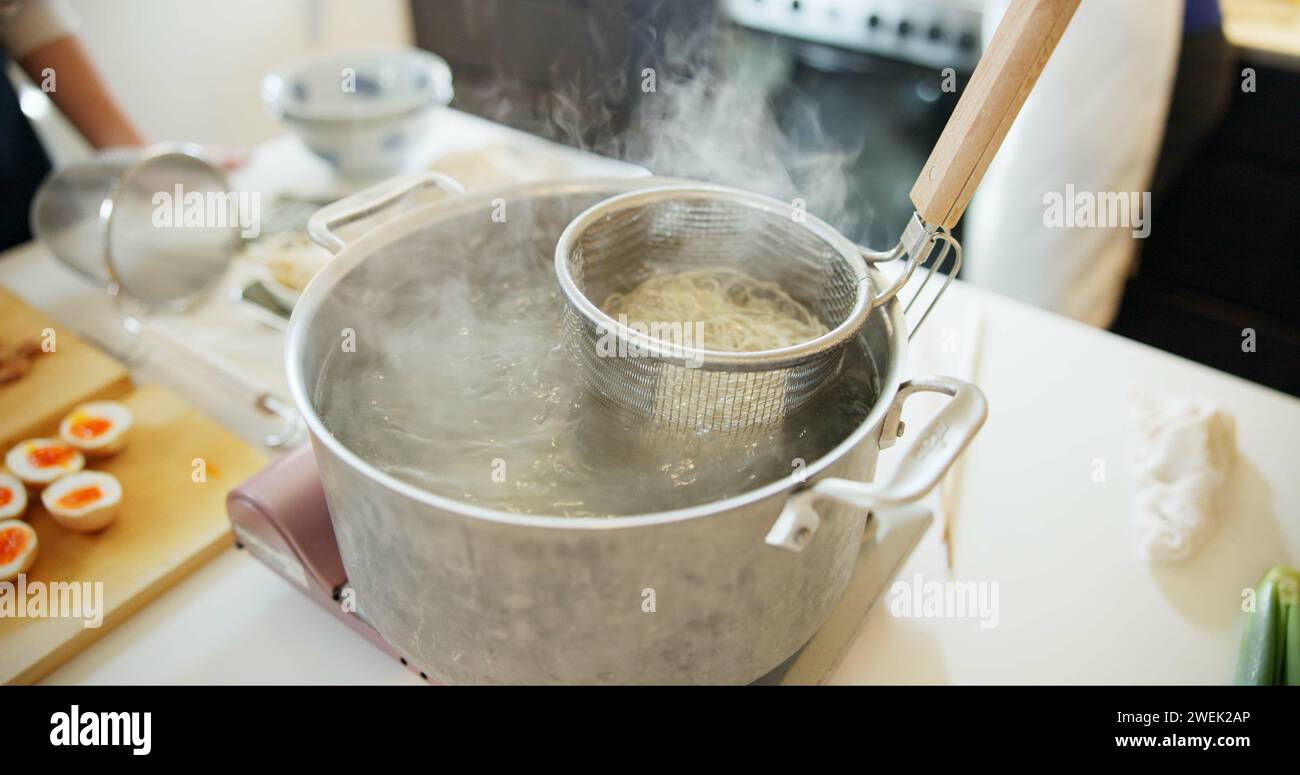 Cooking, kitchen and Japanese noodles in pot in boiling water for lunch ...