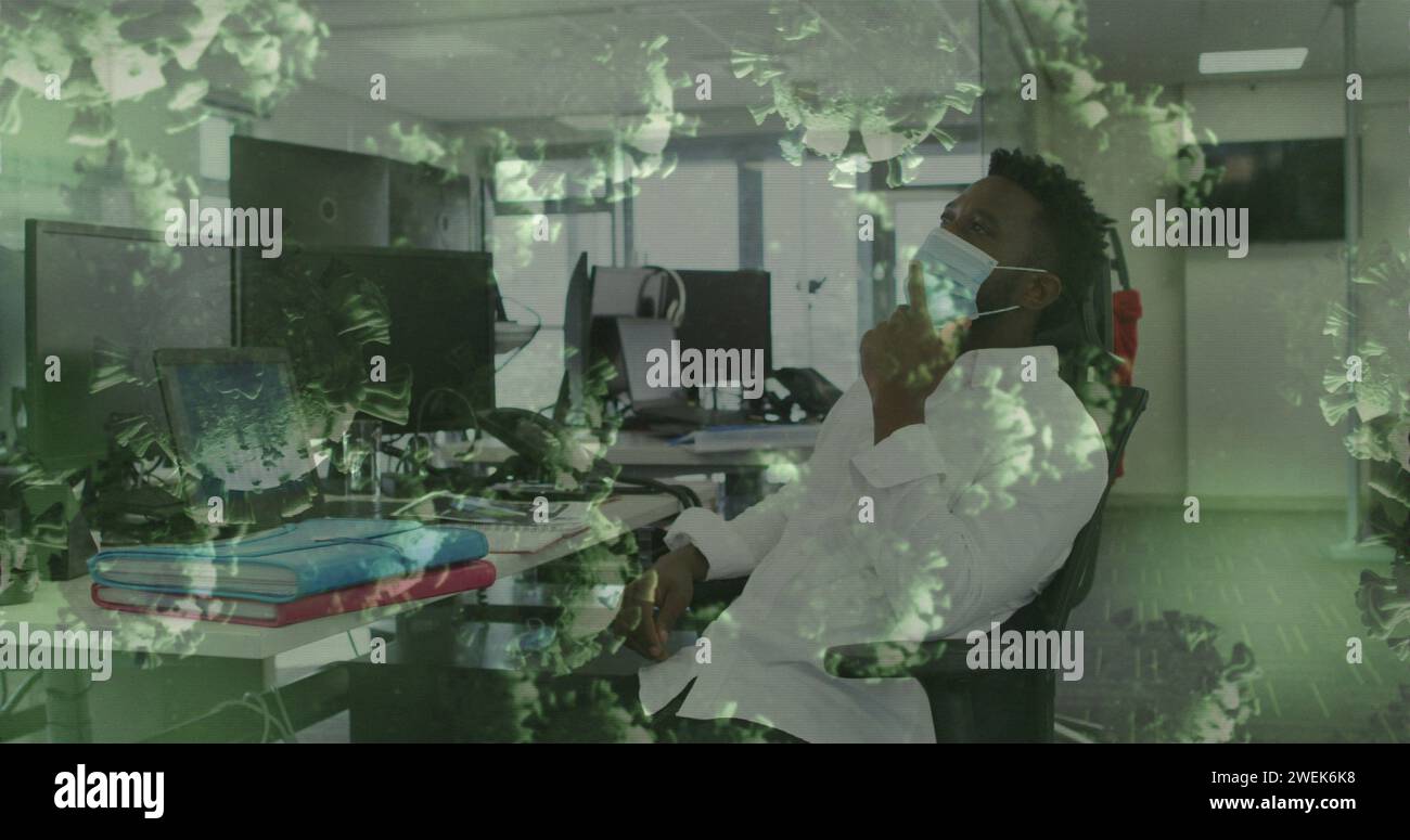 Image of floating covid-19 cells with man in office wearing face masks ...