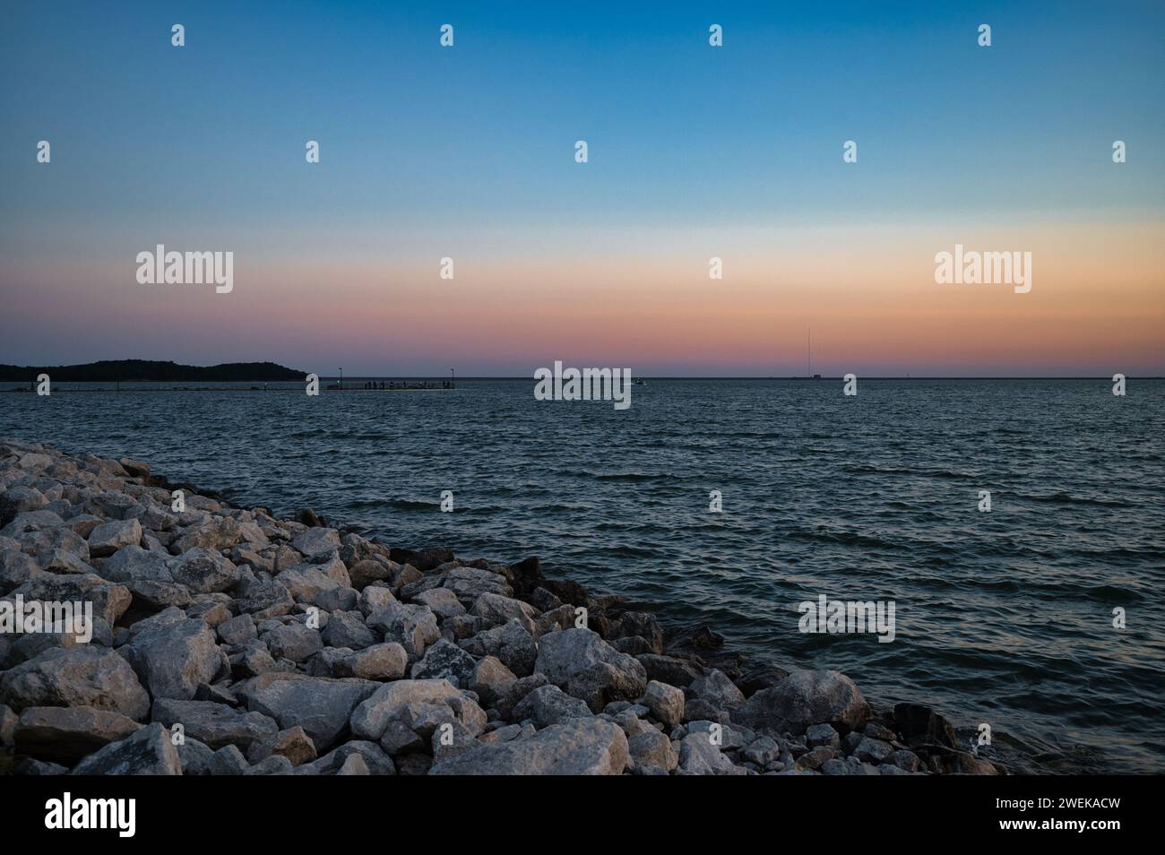 Silhouetted lighthouse against purple sunset sky over ocean Stock Photo ...
