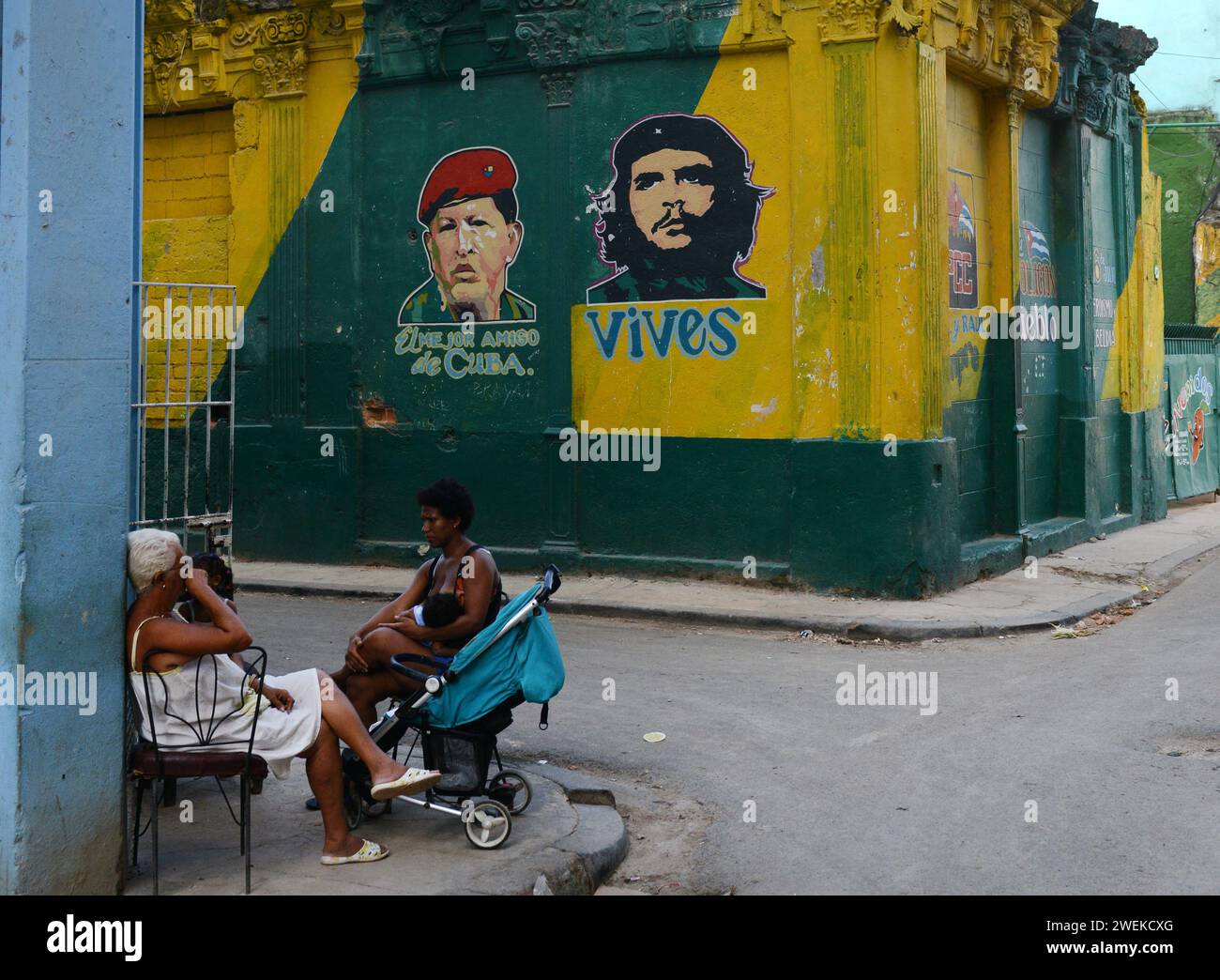 Cuban women socializing by a painted building with the portraits of ...