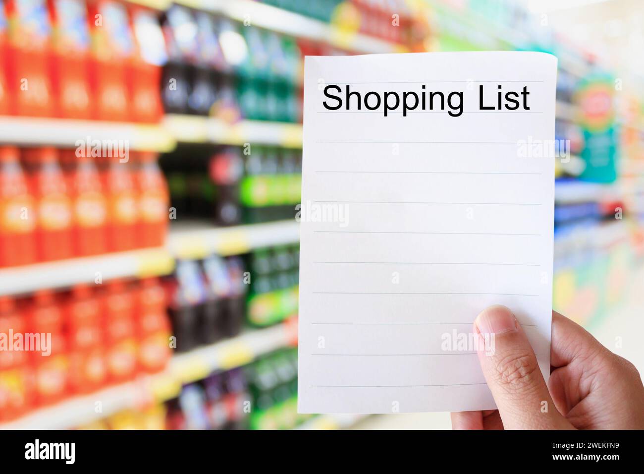 hand hold shopping list paper over soft drink bottles on shelves in ...