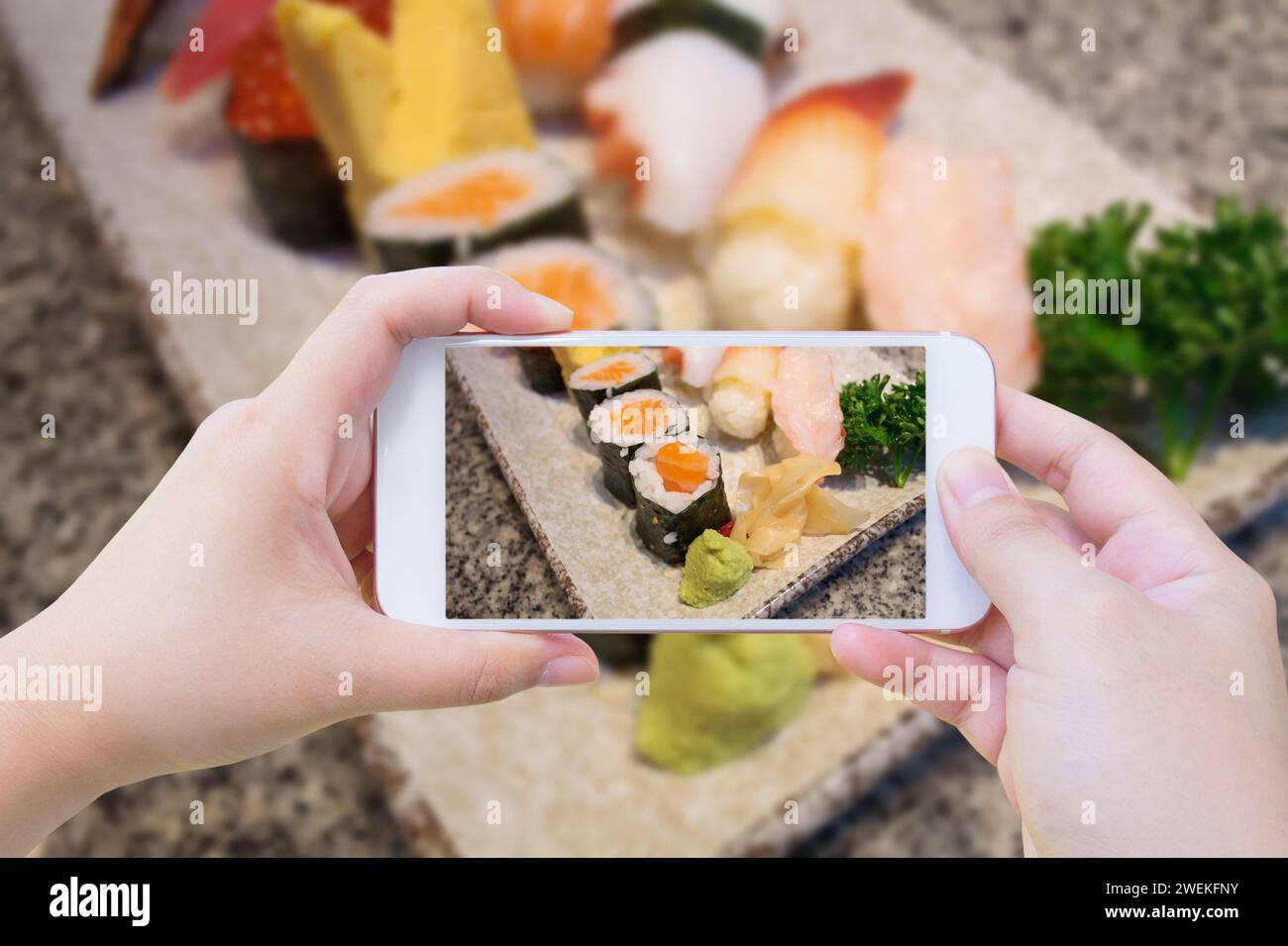 Female using mobile smart phone Taking photo of Japanese sushi set ...