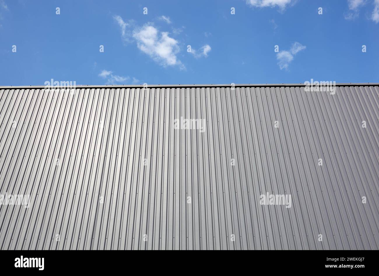 Corrugated steel warehouse or factory industrial building against blue sky. Architecture. Metal ...
